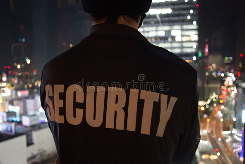 Closeup Shot of a Security Guard Looking Down the CityÂ full of Lights ...