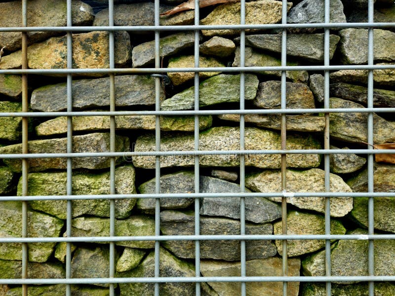 Closeup of a Stone Wall Texture Behind a Metallic Cage Stock Photo ...