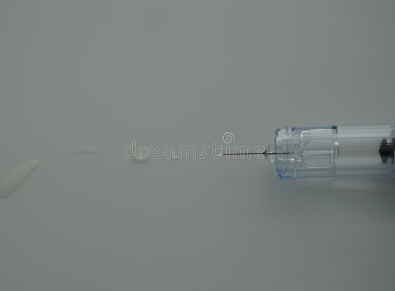 Closeup of a Syringe Filled with a Liquid with Drops at the End of the ...