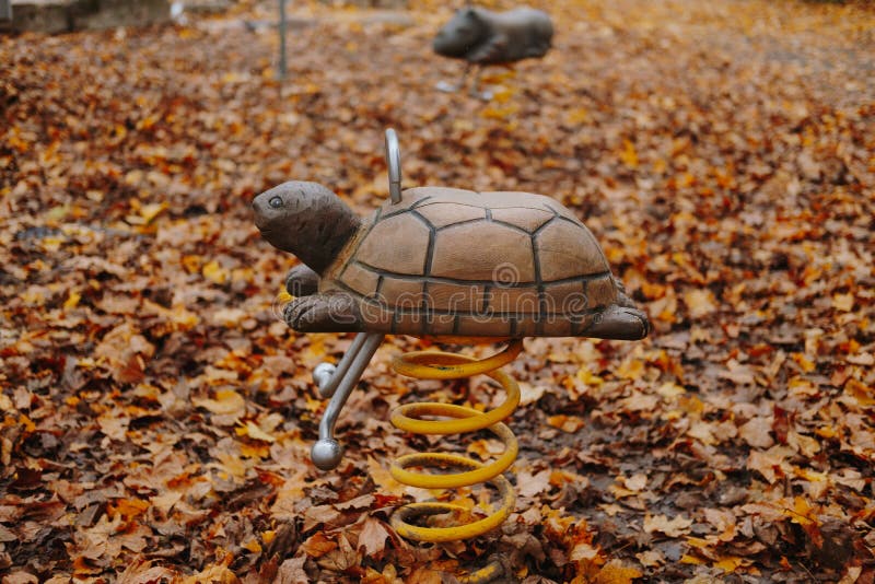 Closeup of a Turtle-shaped Spring Rider in a Park Covered in Dry Leaves ...
