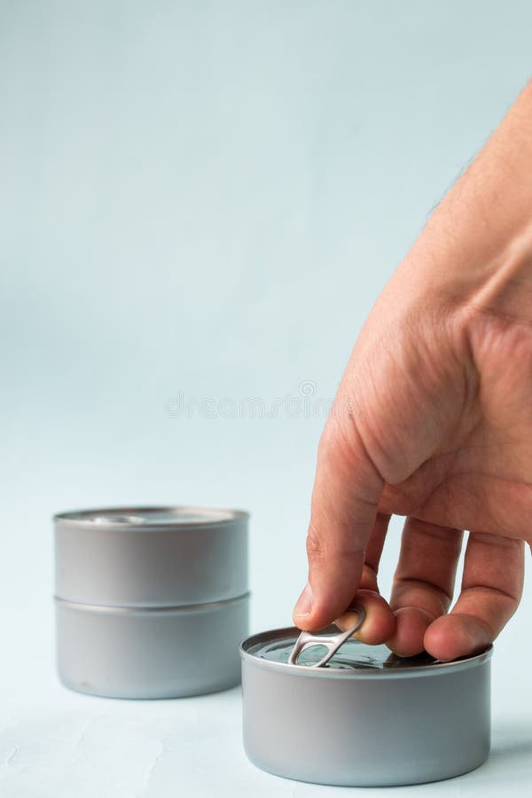 Closeup Vertical Shot of a Hand Opening a Tin Can with Two Stacked Cans ...
