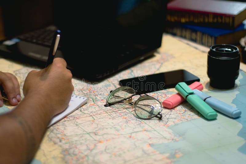 Closeup View of a Person Writing Notes in a Notebook with a Map ...