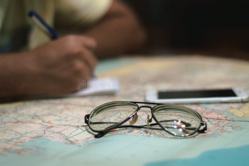 Closeup View of a Person Writing Notes in a Notebook with a Map ...