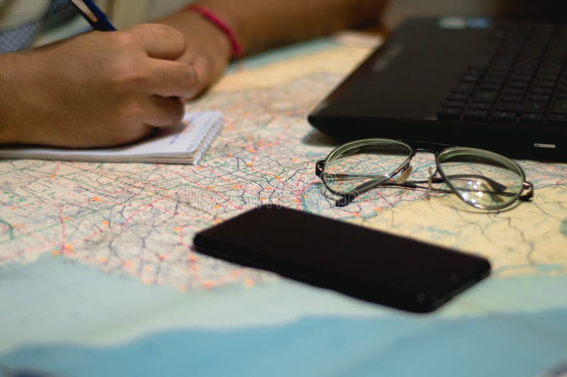 Closeup View of a Person Writing Notes in a Notebook with a Map, Mobile ...