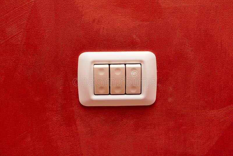 Closeup of a White Panel with Three Light Switches on a Red Concrete ...