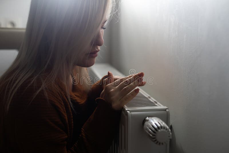 Closeup Of Woman Warming Her Hands On The Heater At Home During Cold