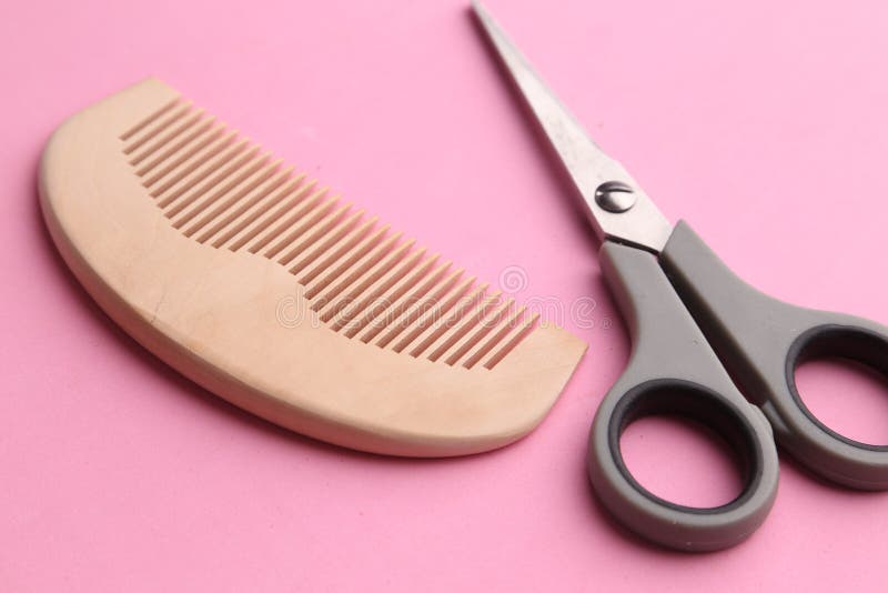 Closeup of a Wooden Comb and Scissors on Pink Surface Stock Photo ...
