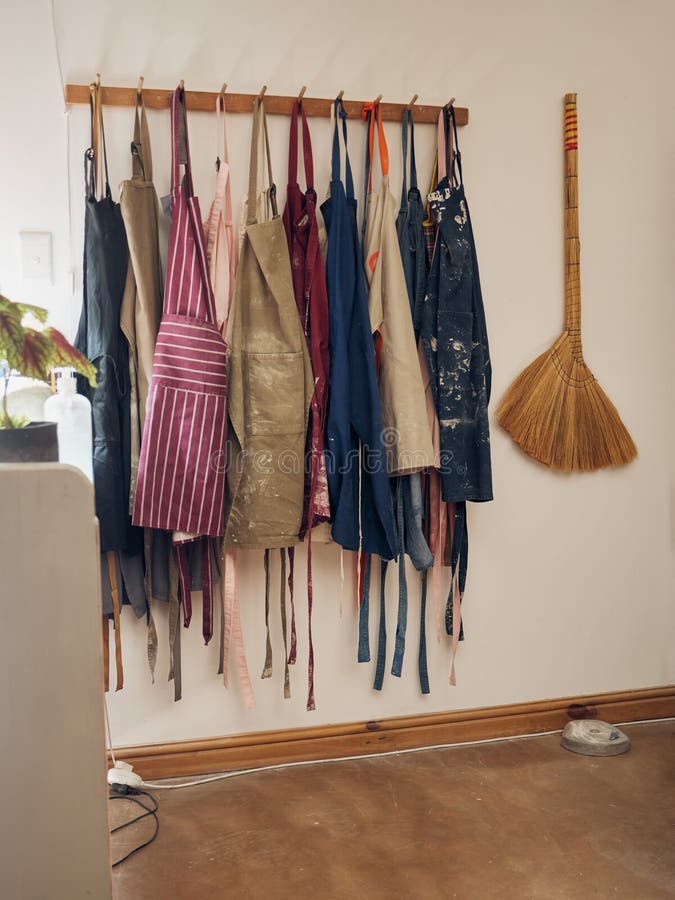 Clothes Rack, Apron and Pottery with a Broom in an Empty Workshop or ...
