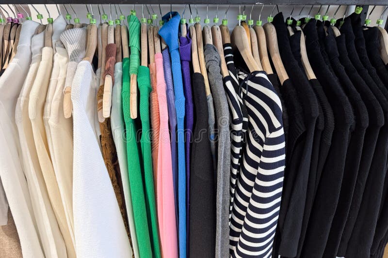 A Clothing Rack Displays an Organized Row of Sweaters and Tops in a ...