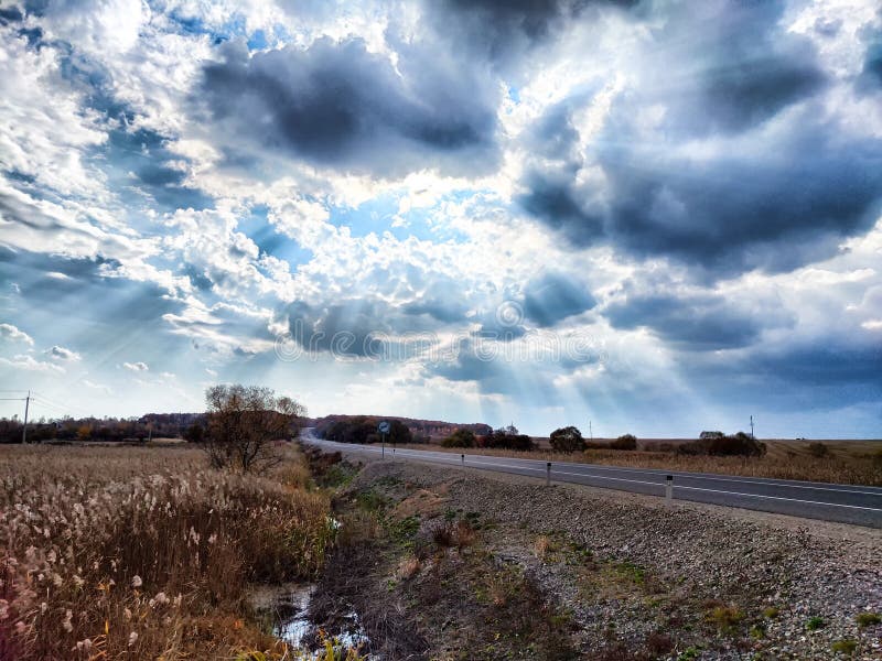 Clouds Parting Over a Country Road at Midday with Fields and Distant ...