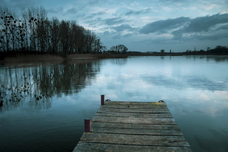 Cloudy and Cold Winter Evening, Freezing Lake with a Pier Stock Image ...