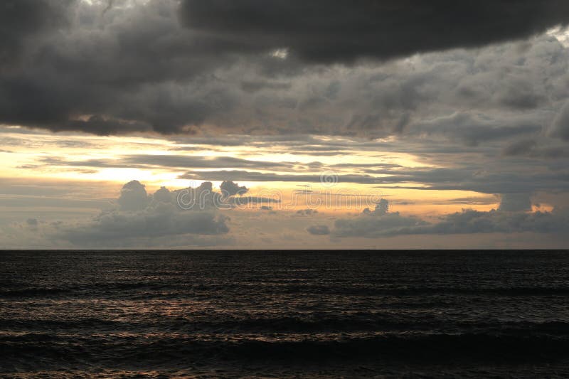 A Cloudy Sky Over the Ocean with a Dark Sky and the Sun Setting Behind ...