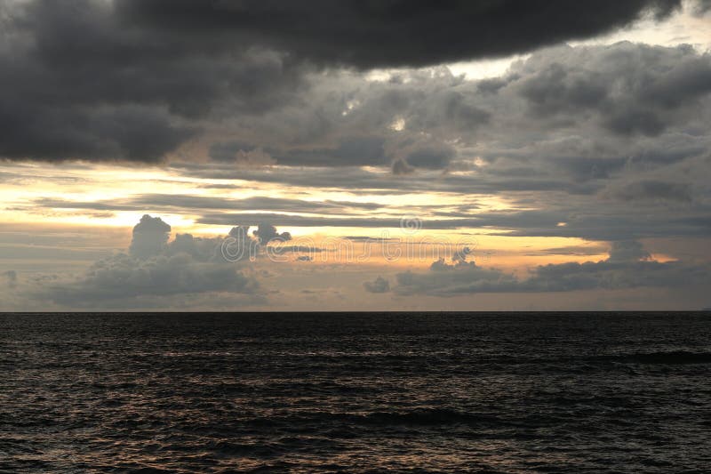 A Cloudy Sky Over the Ocean with a Dark Sky and the Sun Setting Behind ...
