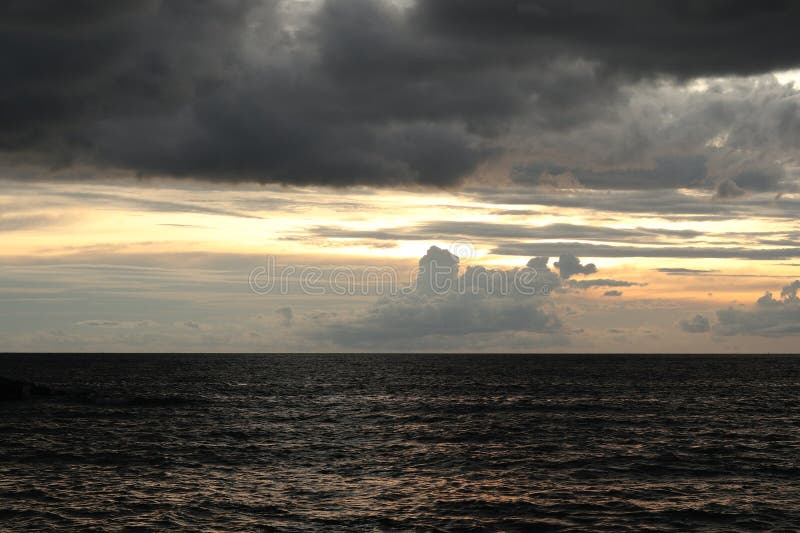A Cloudy Sky Over the Ocean with a Dark Sky and the Sun Setting Behind ...