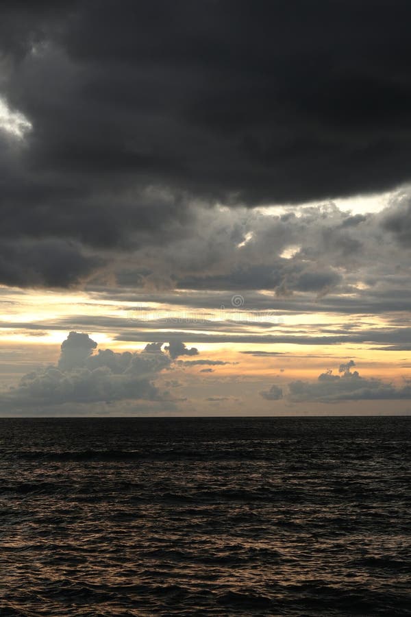 A Cloudy Sky Over the Ocean with a Dark Sky and the Sun Setting Behind ...