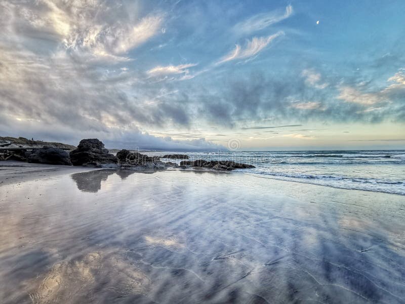 Cloudy Sky Reflecting in the Smooth Surface of an Ocean Beach at Sunset ...