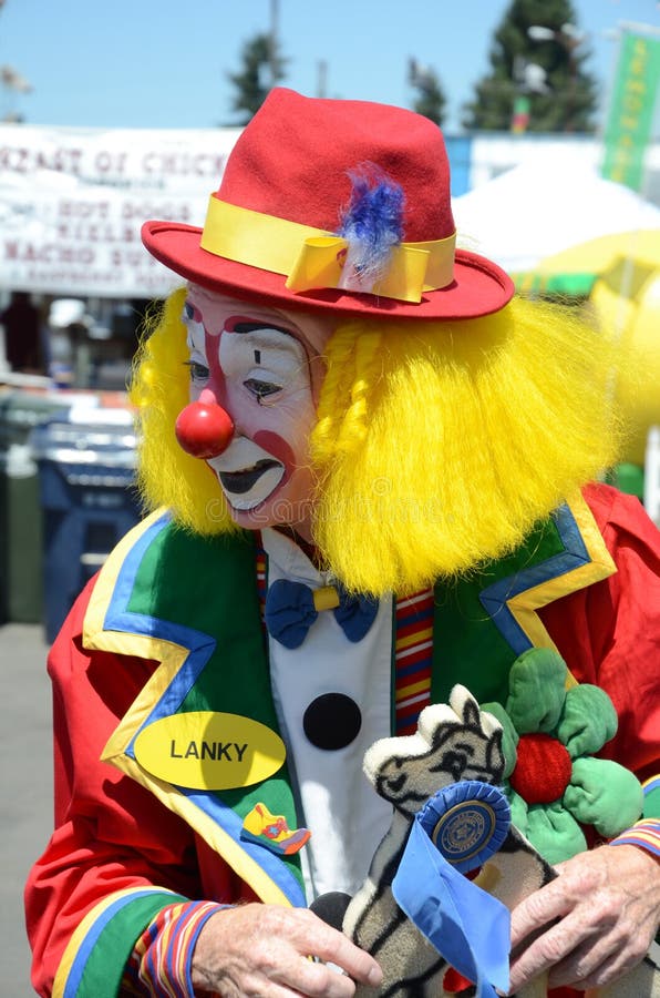 Friendly Clown on Stilts Smiling Widely while Posing with Children at ...