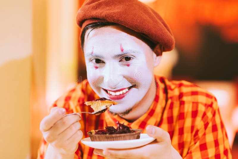 The Clown is Eating a Cake in a Cafe and His Face is Croaking. Stock ...