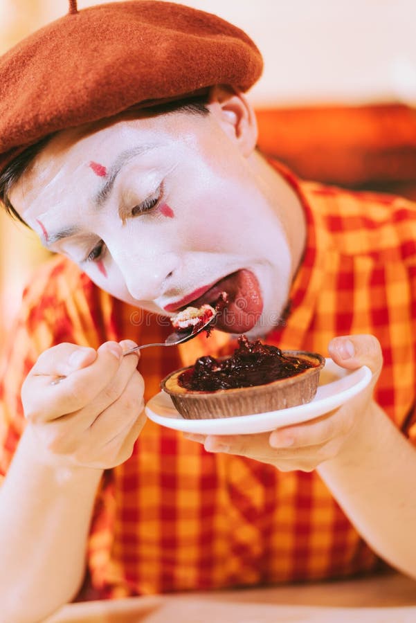 The Clown is Eating a Cake in a Cafe and His Face is Croaking. Stock ...
