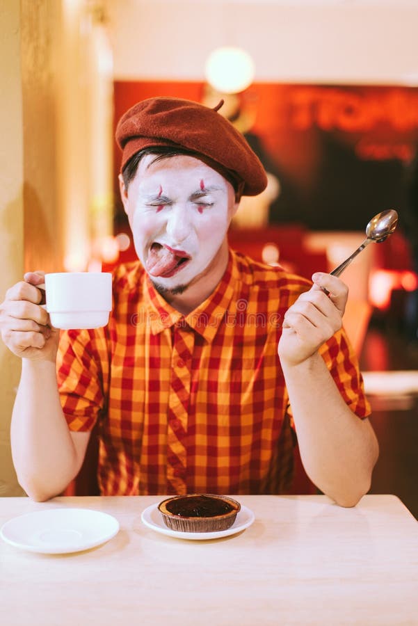 The Clown is Eating a Cake in a Cafe and His Face is Croaking. Stock ...