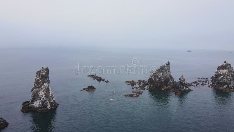A Cluster of Rocks Emerges from the Mist in the Middle of the Ocean ...