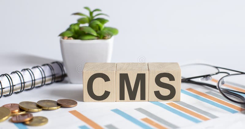 CMS Word on Wood Blocks Concept with Chart, Coins, Notebook and Glasses ...