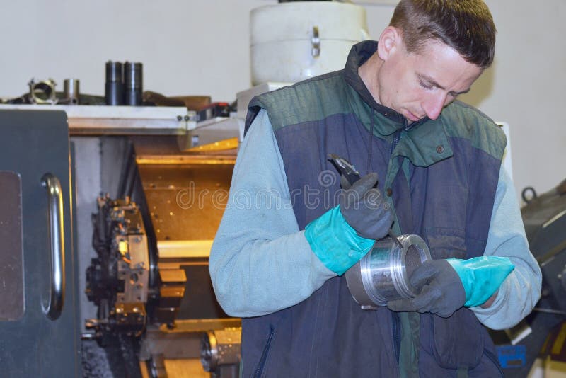 CNC-machinist at Work. he Checks Metal Part Which Was Already Produced ...