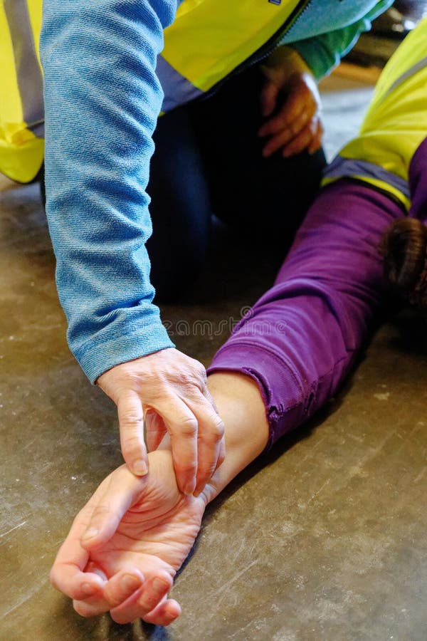 Co Worker Checking the Pulse on a Woman Lying on the Floor Stock Image ...