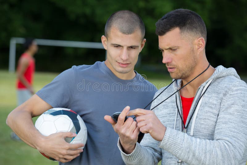 Coach with Footballer Looking at Stopwatch Stock Image - Image of ...