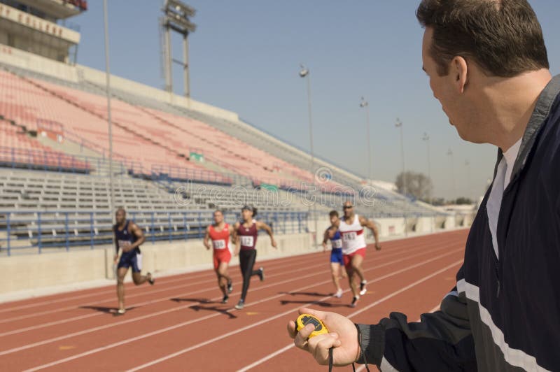Coach with Stopwatch while Athletes Racing in Racetrack Stock Photo ...