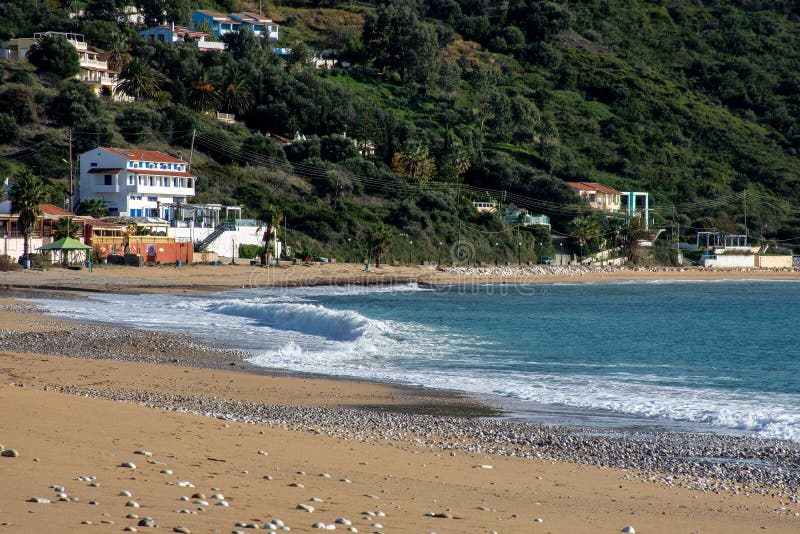 Coastal Beach Scene with Waves Gently Rolling Ashore, Buildings Perched ...