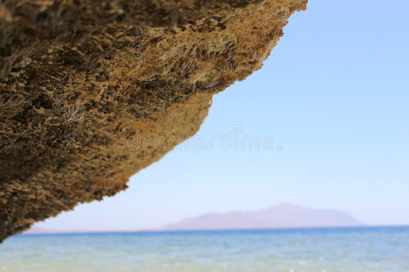 Coastal Rock Overhang Framing a Serene Ocean View with Distant ...