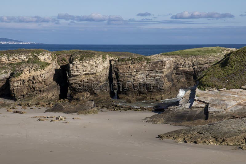 A Coastal Scene with Layered Rock Cliffs, a Sandy Beach, and a Clear ...