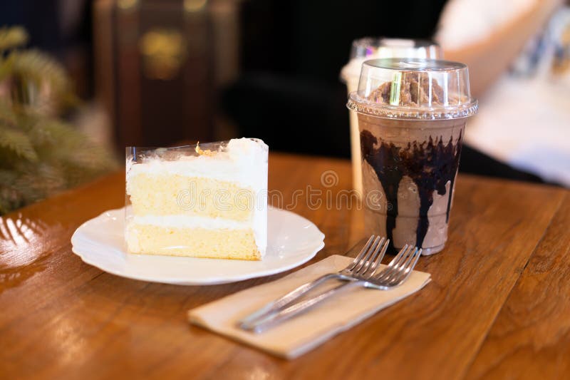 Coconut Cake on White Plate and Cold Drink on Wooden Table in Bakery or ...