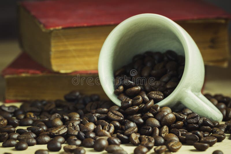 Coffee Bean in Tilted Ceramic Cup and Old Book Laid Behind. Stock Photo ...