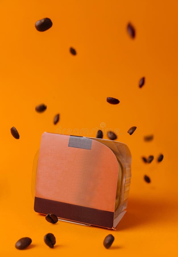 Coffee Beans Falling Around Coffee Packaging on Orange Background Stock ...