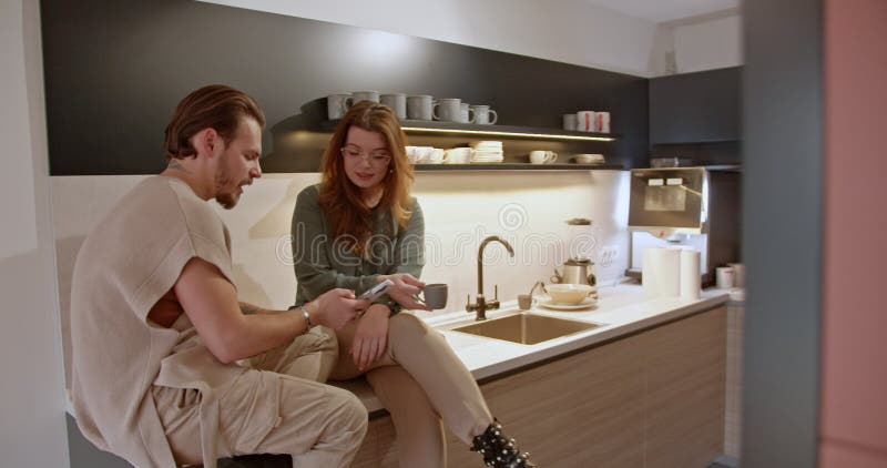 Two Colleagues Sitting in the Office Kitchen on a Countertop, Engaging ...