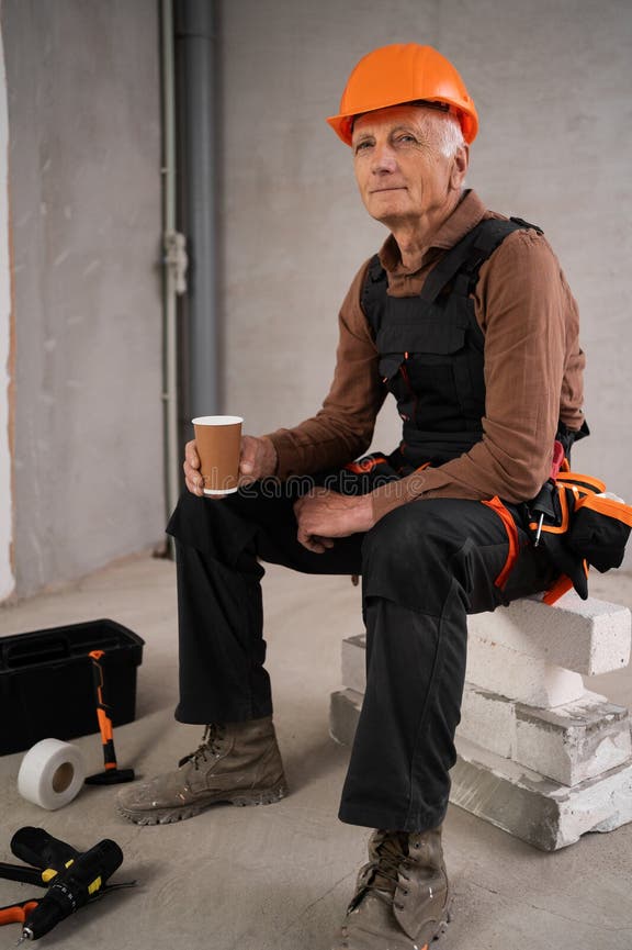 Coffee in Hands of Construction Worker Who Has Break at Construction Site. Old Builder or ...