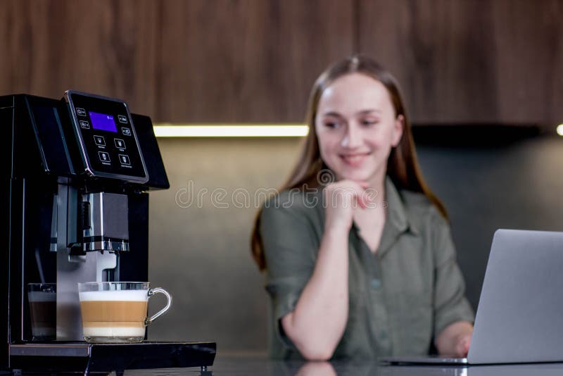 Coffee Machine Prepares Coffee while the Woman Working at the Computer ...