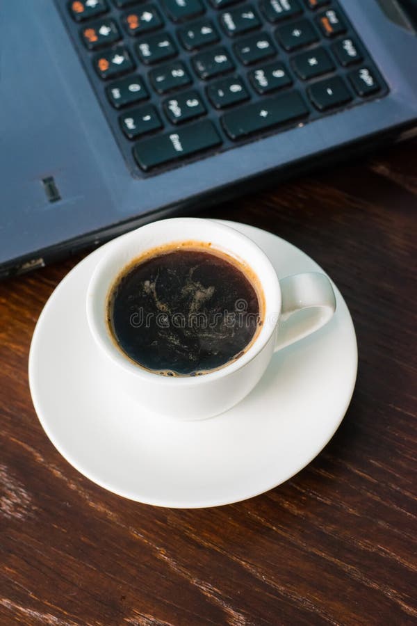 Coffee in a White Cup and a Laptop on the Background on a Brown Wooden ...