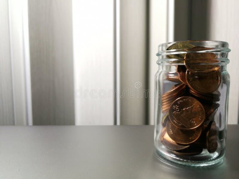 Coins in a Glass Bottle on Empty Desktop and White PVC Blind Curtain ...