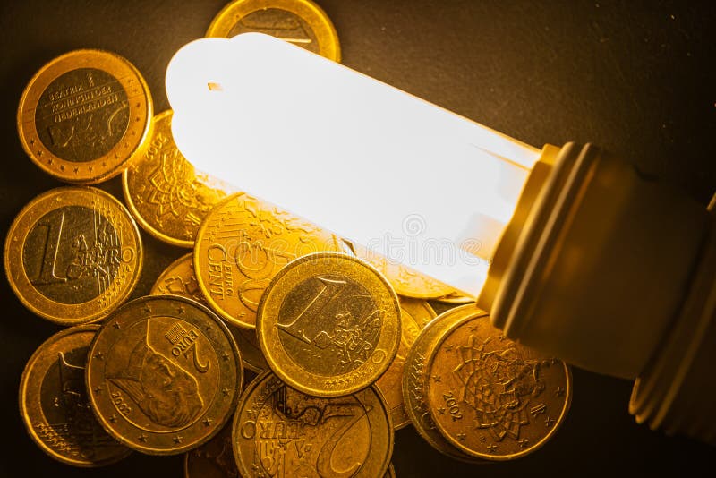 Coins and Light Bulb on a Dark Surface Stock Photo - Image of ...