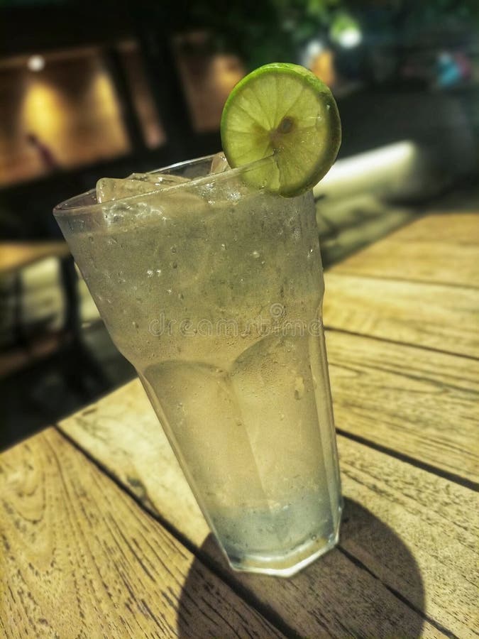 Cold Lychee Splash Glass with Orange Garnish on Wooden Table Stock ...