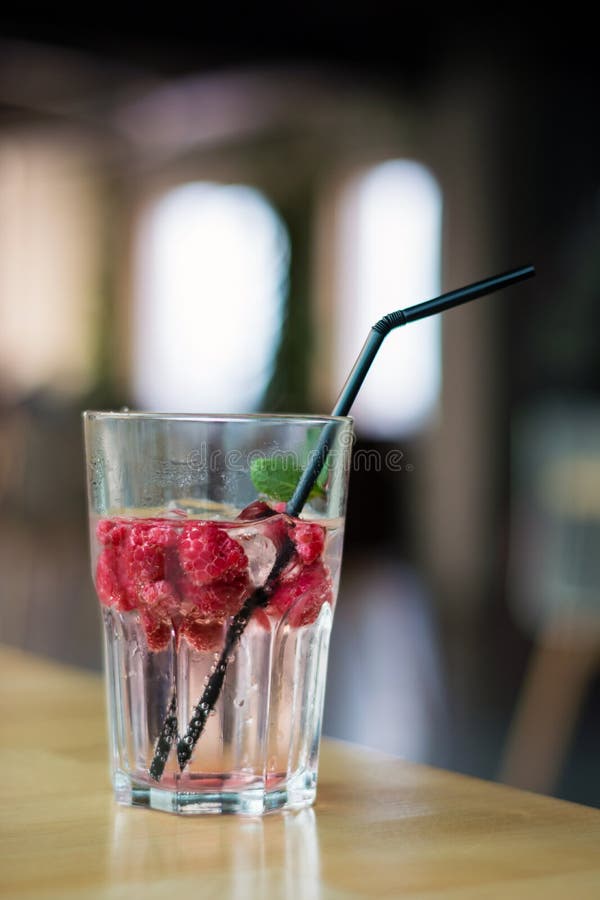 Cold Raspberry Drink with Mint Leaves in a Sweaty Glass on a Table in a ...