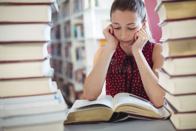 Libro De Lectura Atento De La Colegiala En Biblioteca Foto de archivo ...