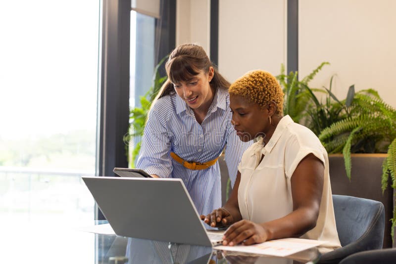 Collaborating on Project, Two Women Using Laptop and Tablet in Modern ...