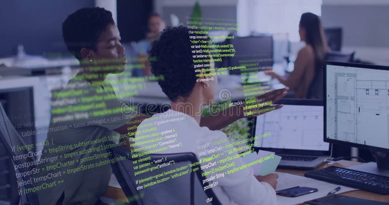 Collaborating Two Women Developers Reviewing Code on Office Monitors, with Keyboard Mouse Laptop ...