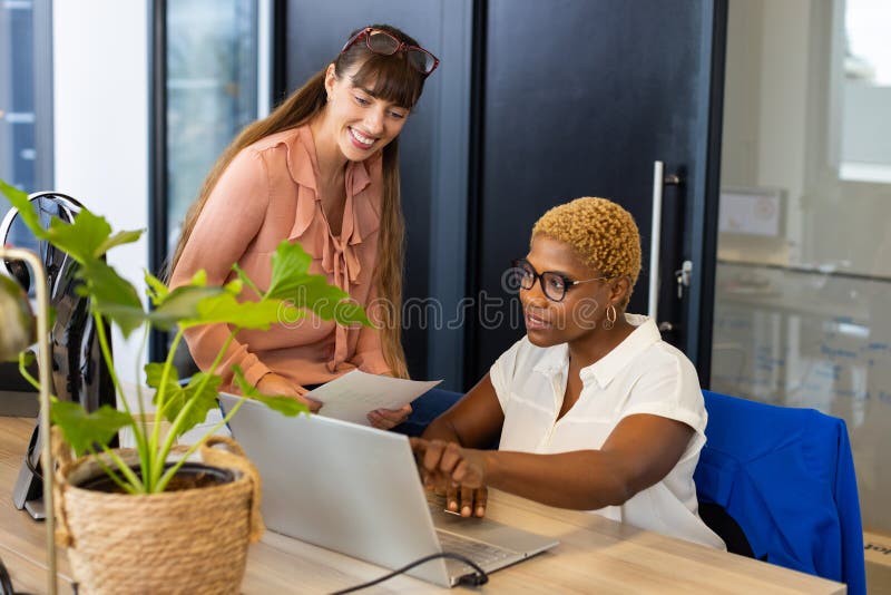Collaborating at Work, Two Women Using Laptop and Discussing Document ...
