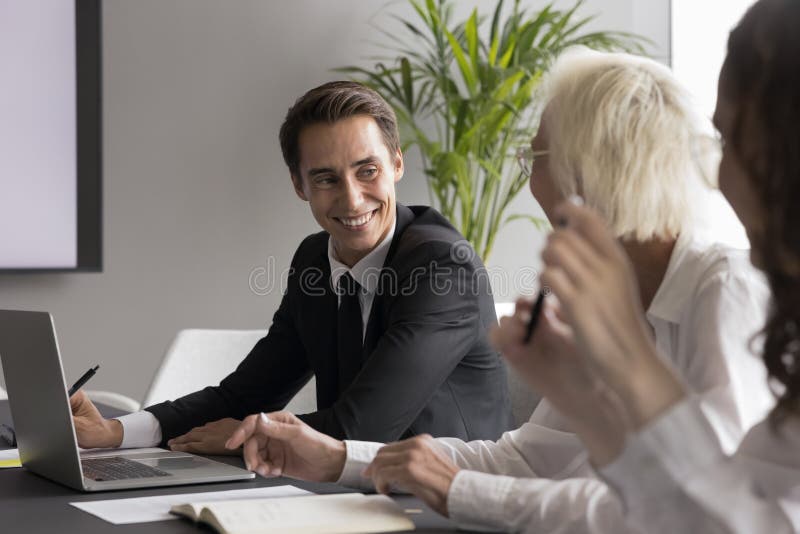 Smiling Businessman Sit by Notebook Listen To Colleagues at Boardroom ...