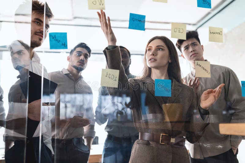 Colleagues Brainstorming Using Sticky Post-it Notes on Glass Wall Stock ...